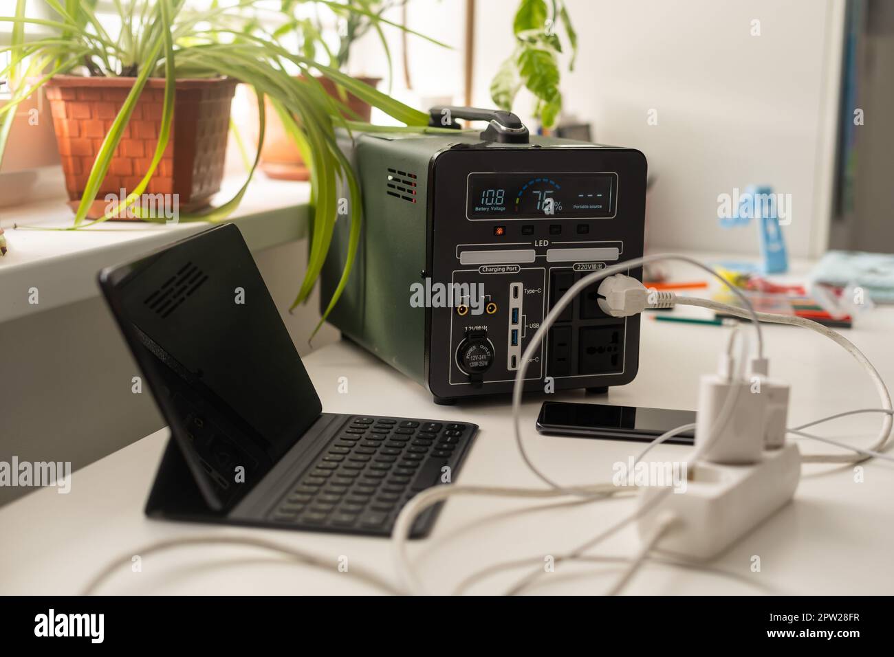 Portable power station charging gadgets near wall Stock Photo - Alamy