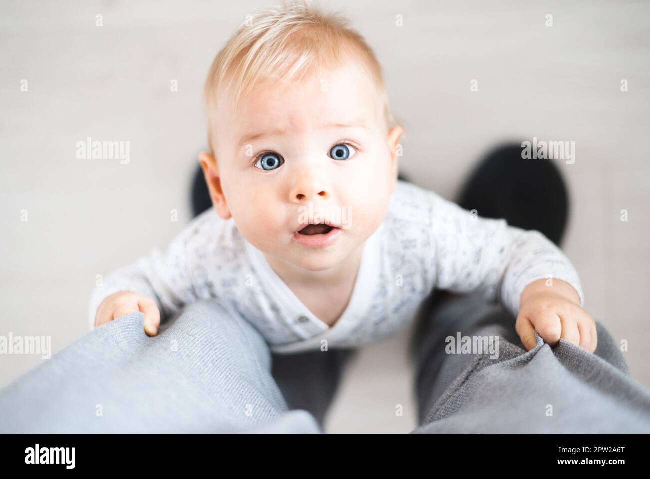 Top down view of cheerful baby boy infant taking first steps holding to ...