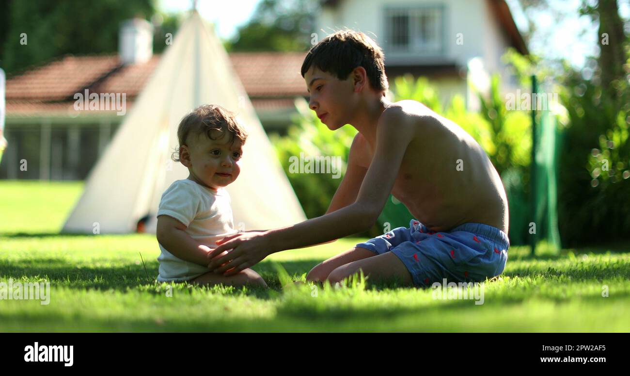 Authentic family moment. Two brothers together outside in garden. Older ...