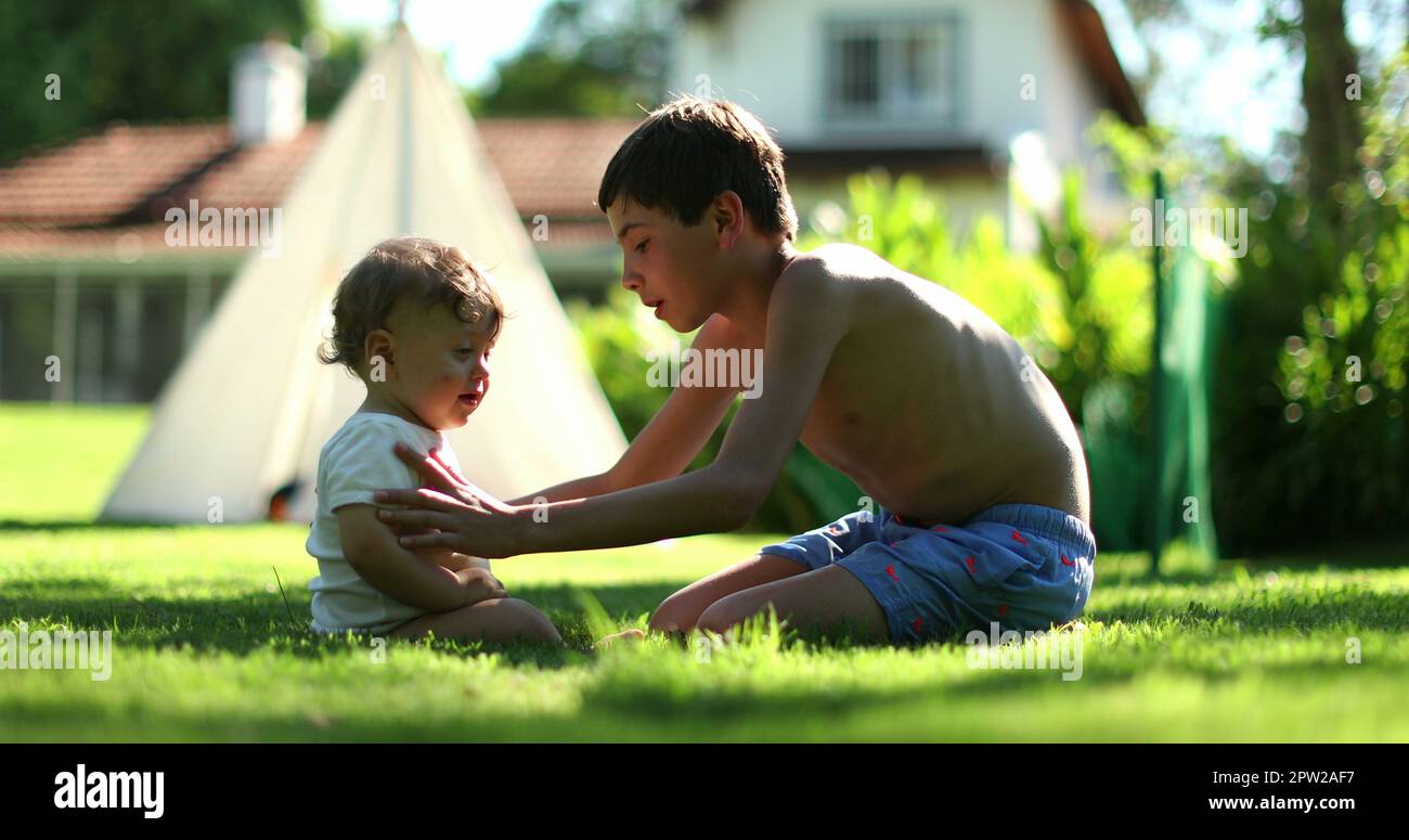 Authentic family moment. Two brothers together outside in garden. Older ...