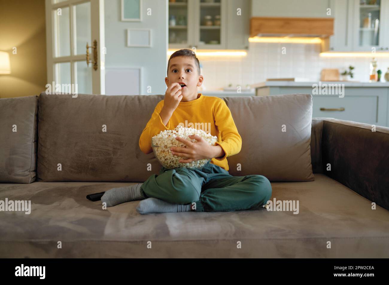 Excited boy child eating popcorn while watching TV with interest ...