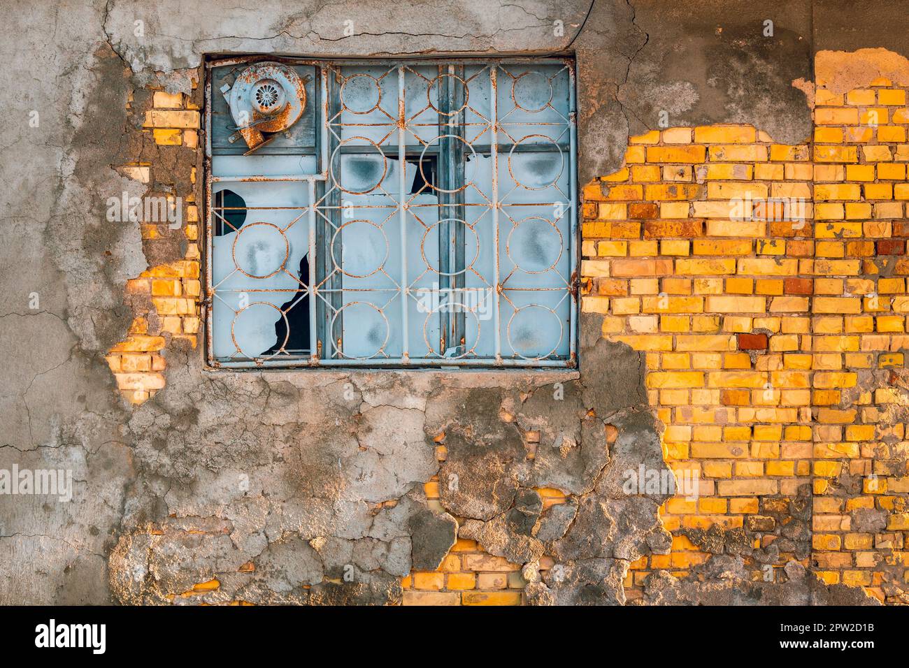 Old window with broken glass and metal bars on a wall of abandoned ...