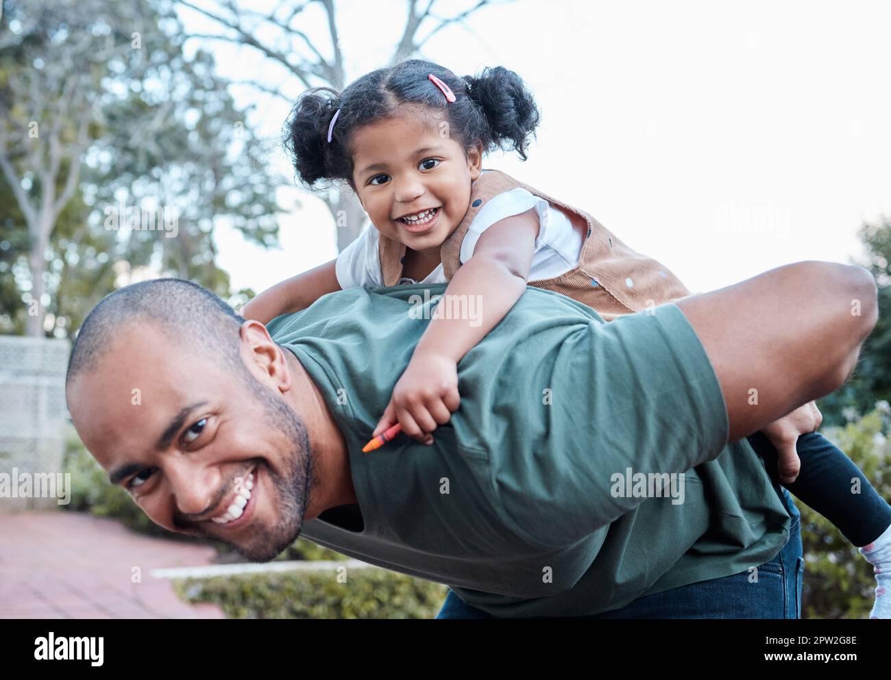 Shot of a man carrying his daughter on his back while standing outside ...