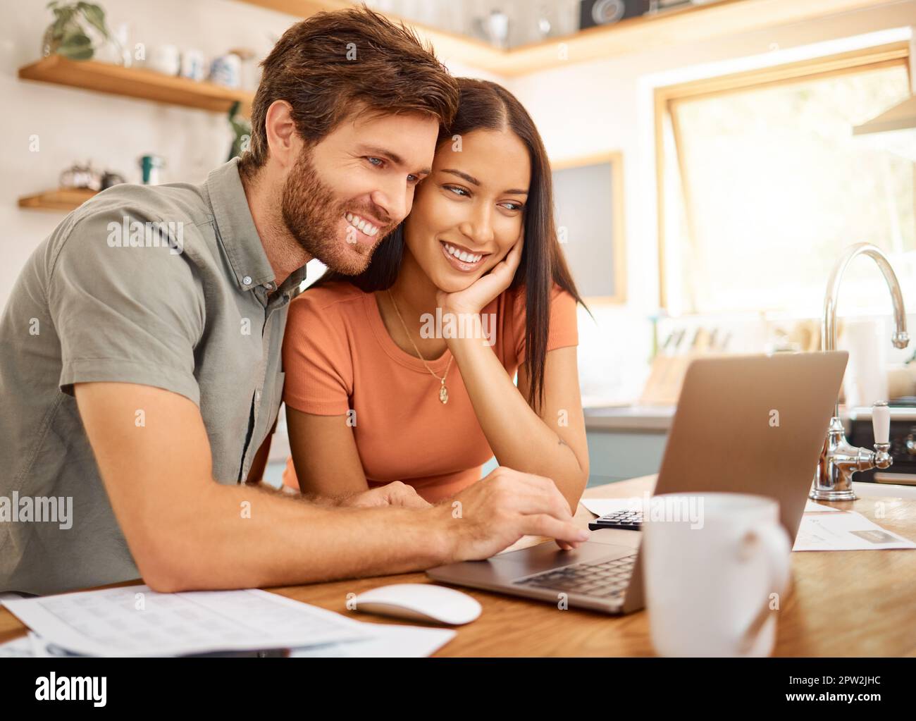 Young cheerful interracial couple bonding while typing on a laptop ...
