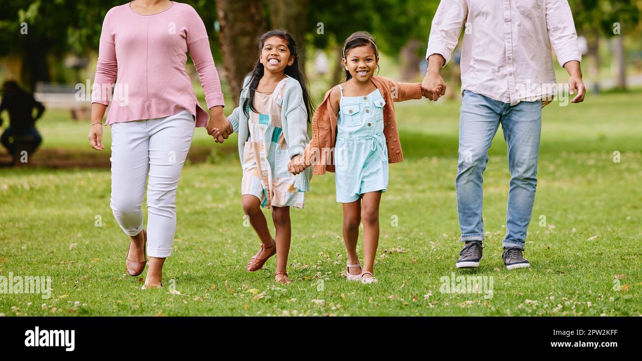 Two adorable little girls walking outside in park with parents. Sibling ...