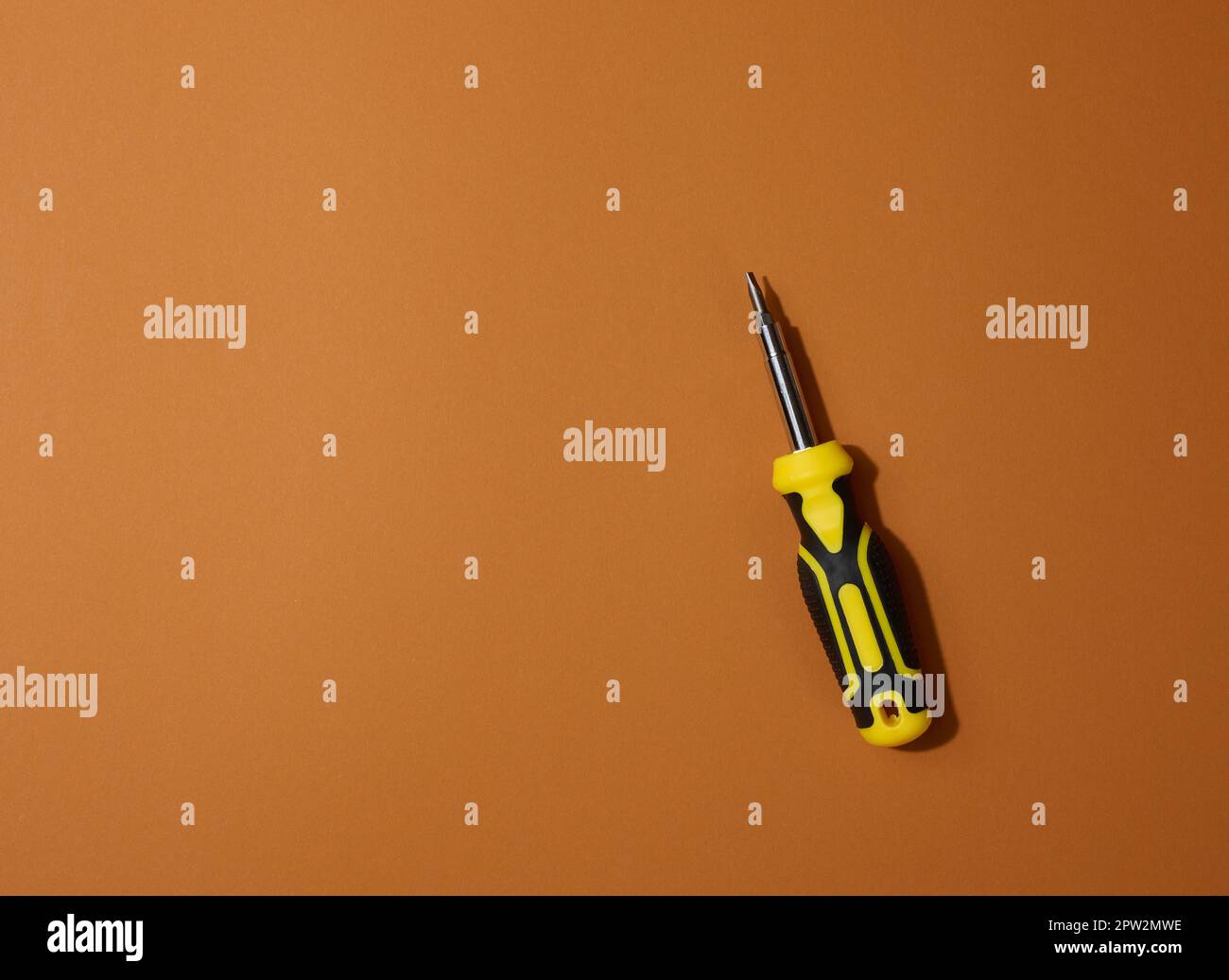 Screwdriver with a rubber handle on a brown background, close up. Copy ...