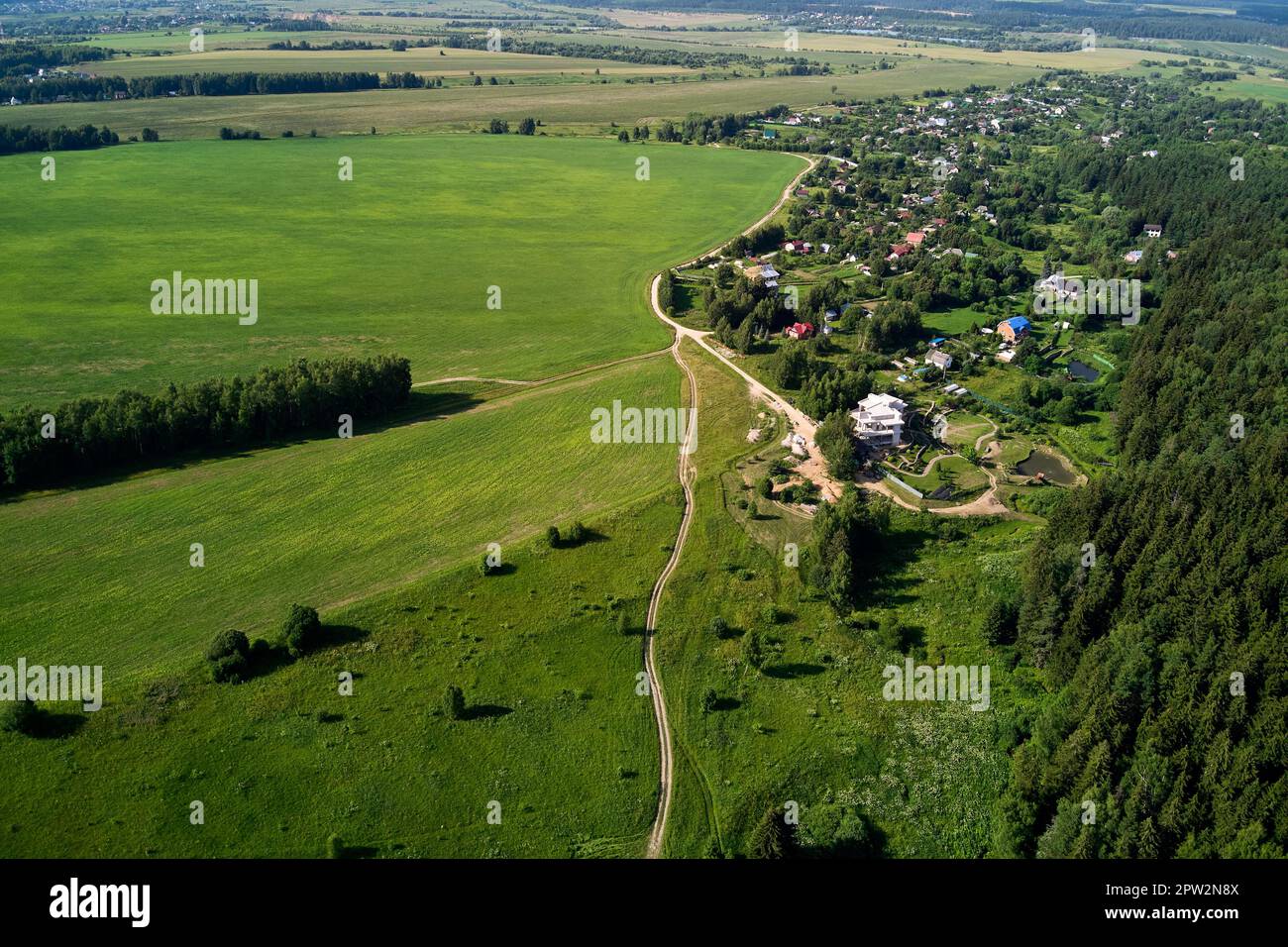 Aerial view of a small village surrounded by green fields and forests ...