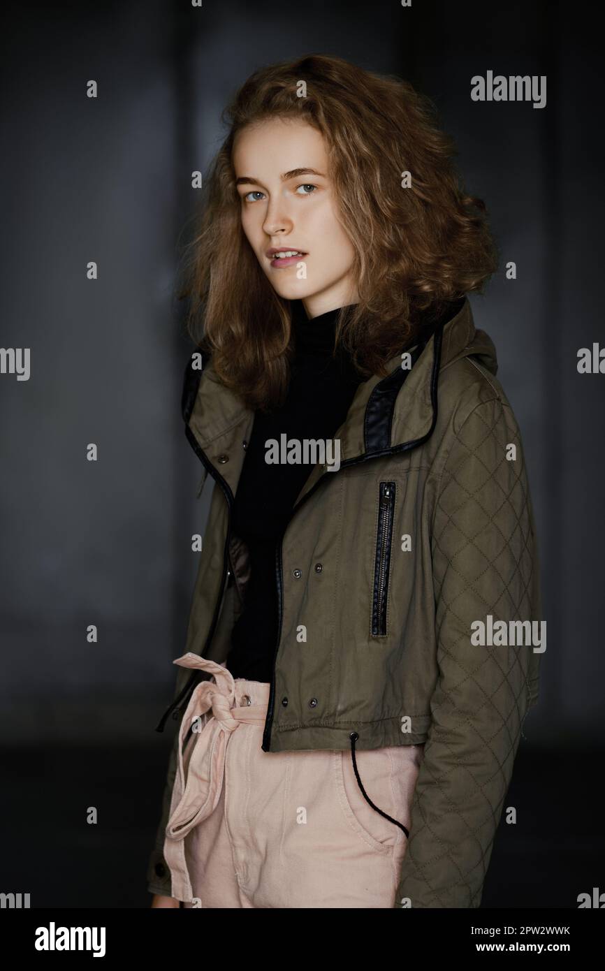 Low key portrait of a student girl in jacket, sweater and trousers ...