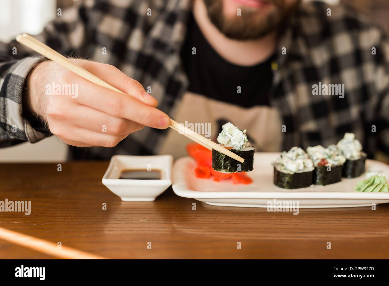 Close up of sushi rolls on a table in a restaurant. Man eating sushi ...