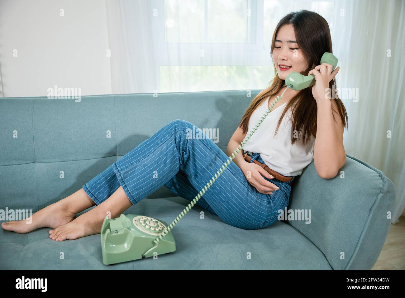 Asian young woman holding green corded telephone handset classic hone ...