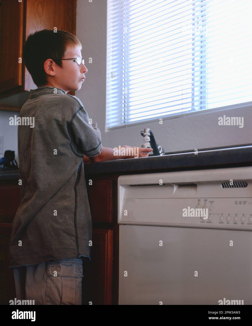 Young boy washing his hands in the kitchen sink Stock Photo - Alamy