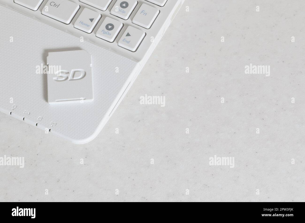 A compact SD memory card lies on a white netbook. The digital ...