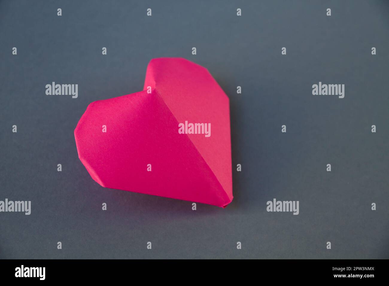 Pink paper heart origami isolated on a blank grey background ...