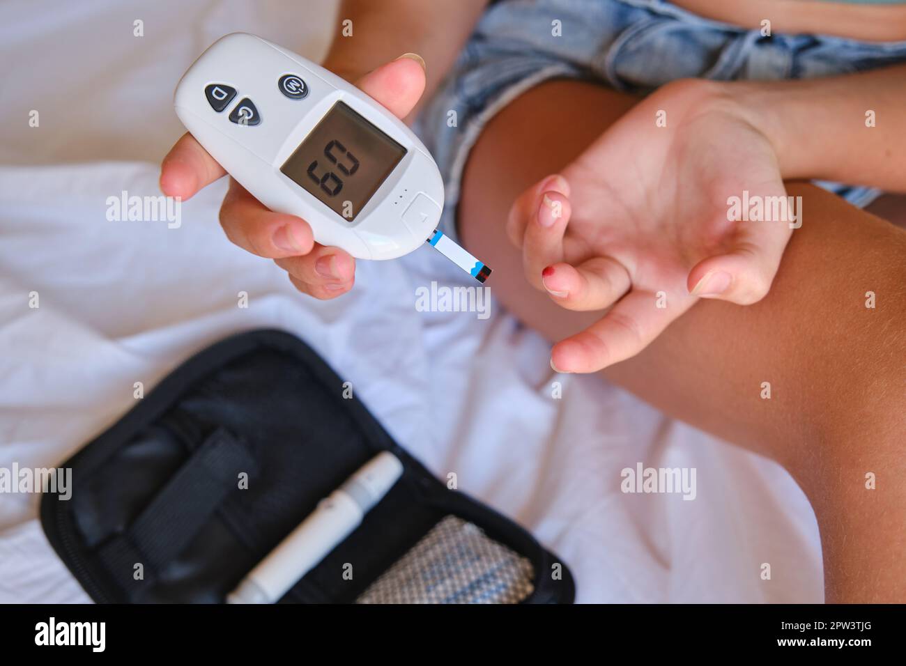 Teenager with diabetes measures blood glucose levels with a glucometer ...