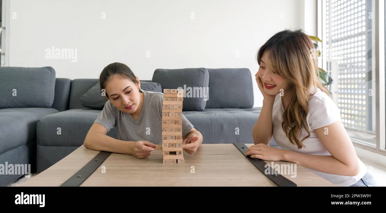 Two asian woman enjoy playing wooden blocks game in the living room ...