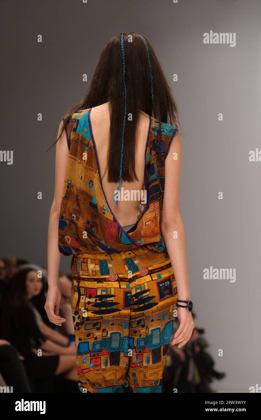 Back view of fashion model in silk dress walking on podium during ...