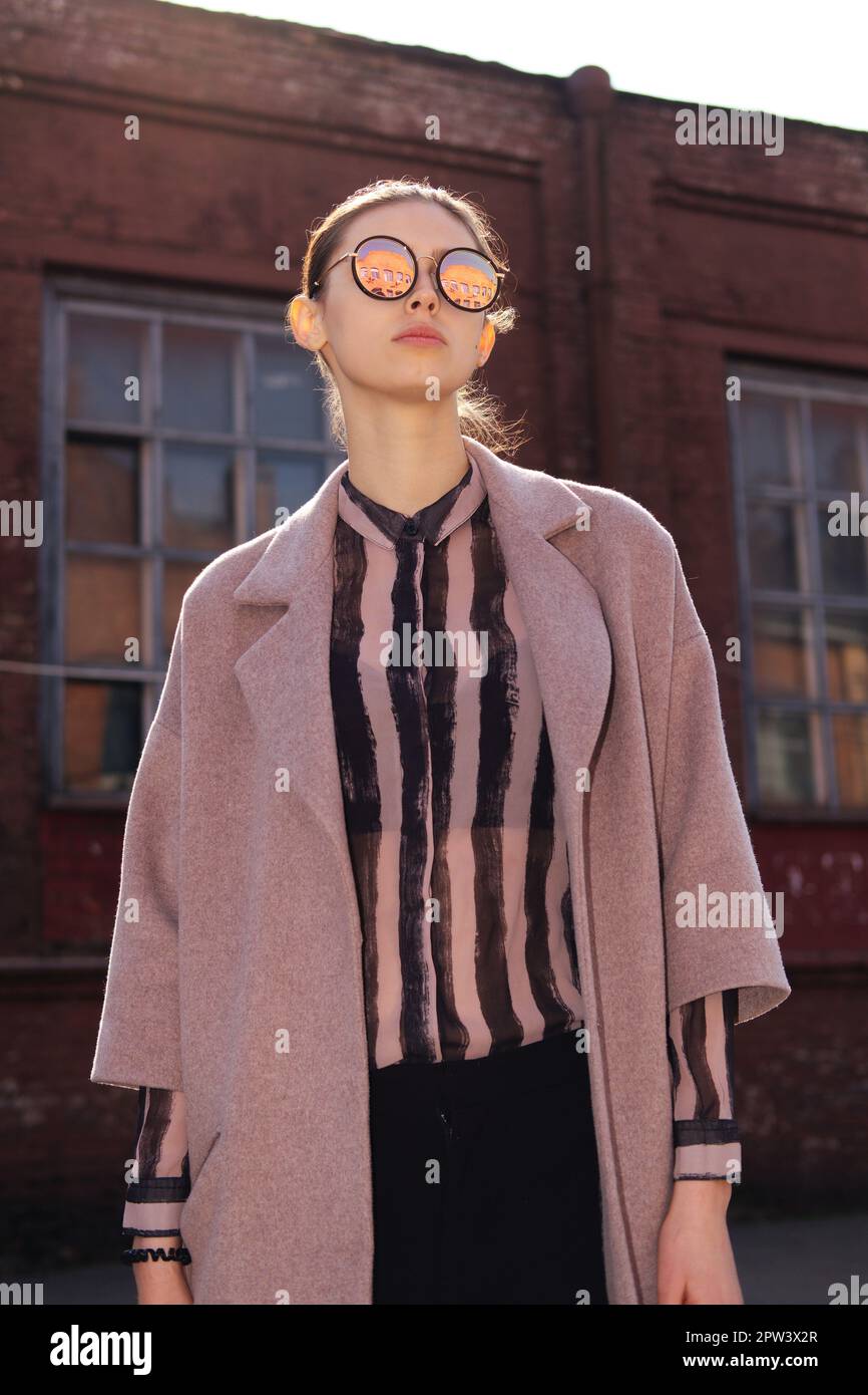 Young girl in unfastened coat enjoying sun. Mirror sunglasses with ...