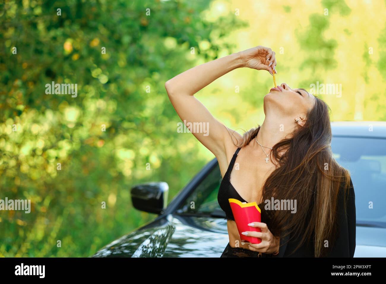 Young woman leaned against the hood of a car on the side of the road ...