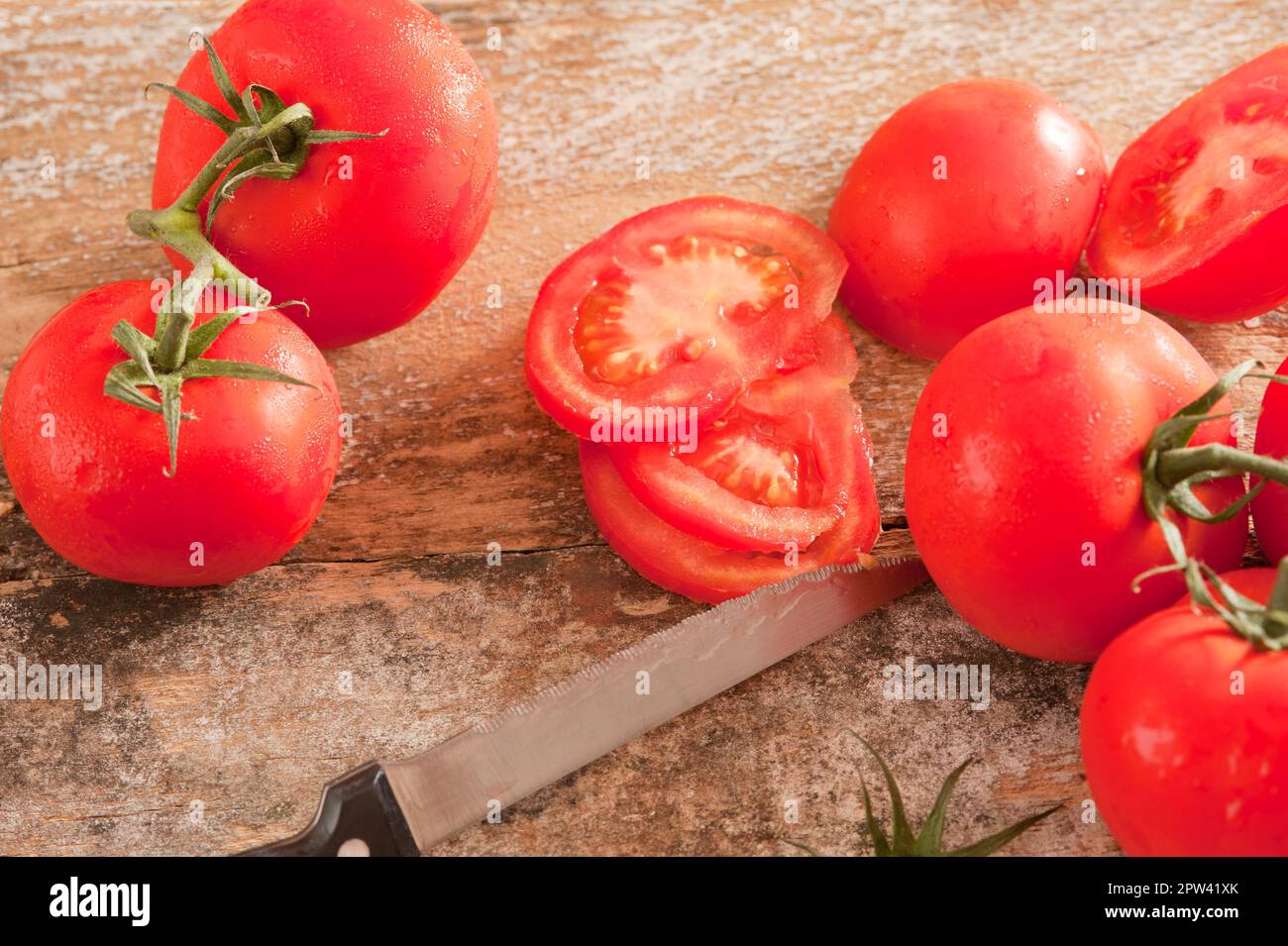 Fresh ripe red truss tomatoes sliced with a serrated kitchen knife on ...