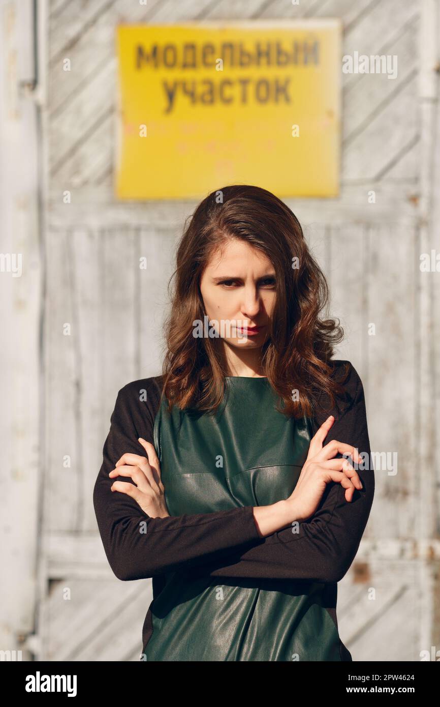 Fashion model posing near factory door with warning plate. (inscription ...