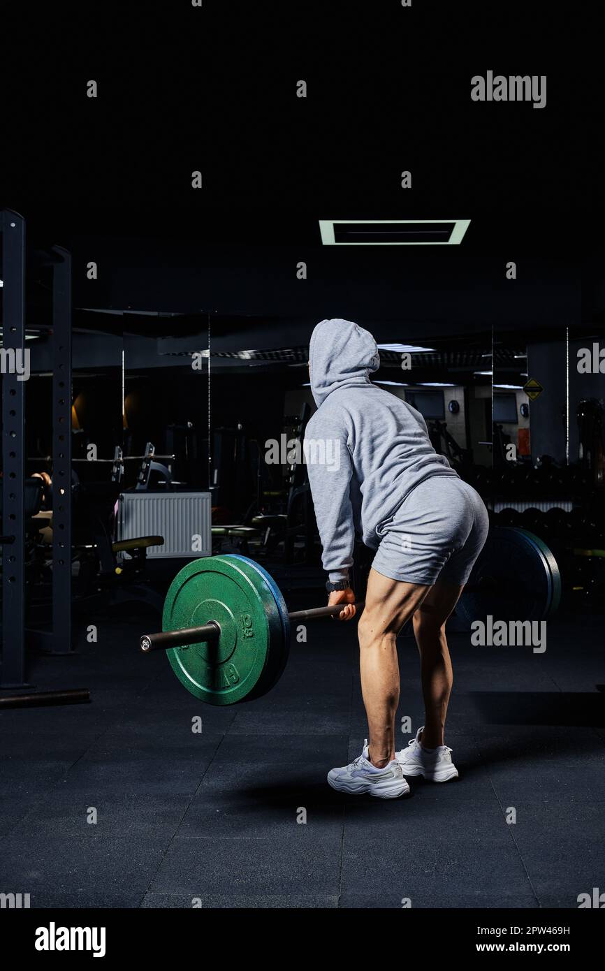 Muscular man doing deadlift exercise with barbell in gym, side view ...