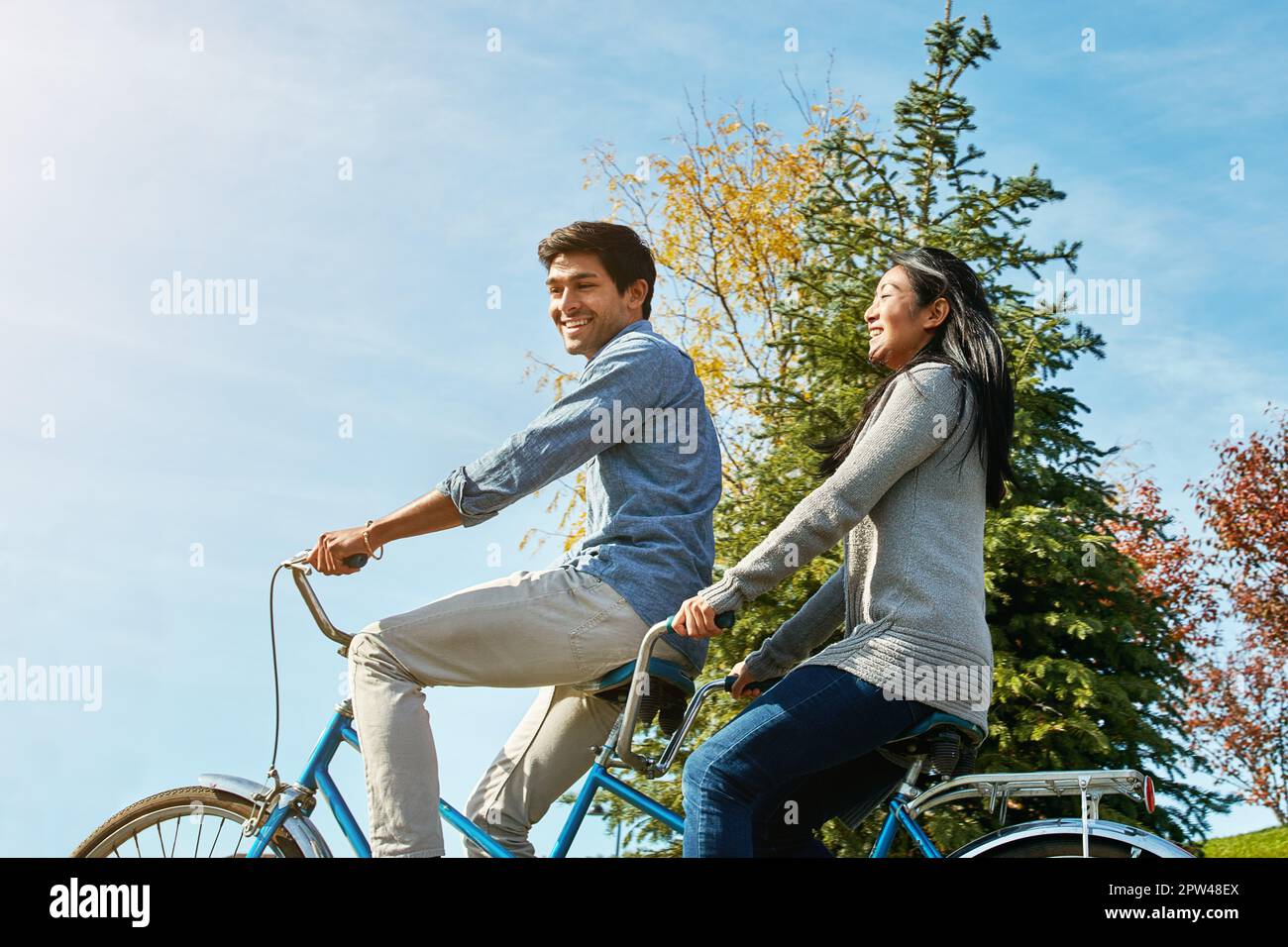 We enjoy the outdoors. a young couple out for a ride on a tandem ...