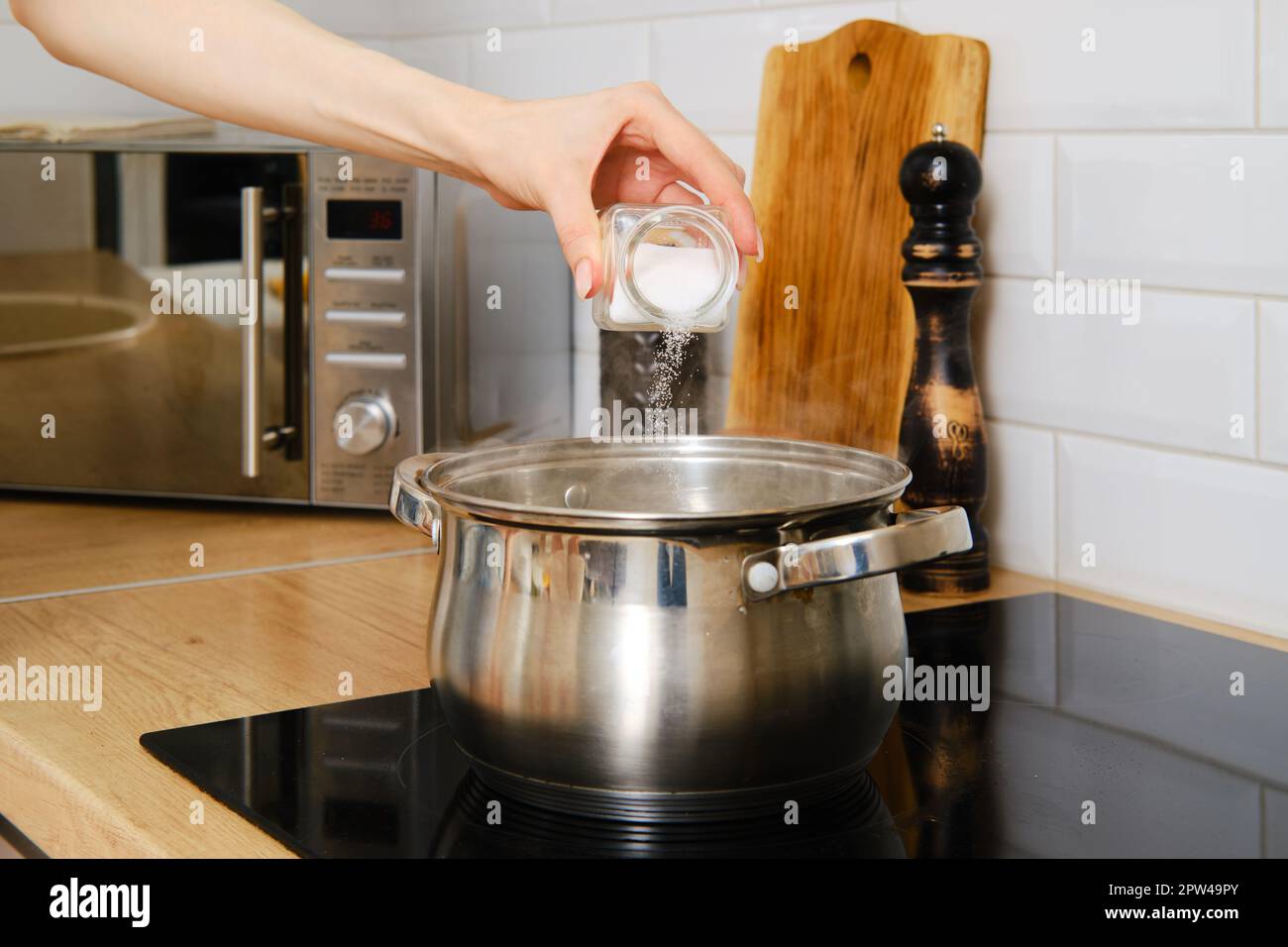 Closeup view of female hand pouring salt to water boiling on electric ...