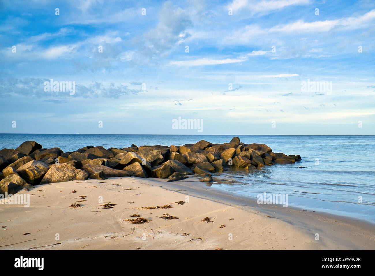 Stone groyne jutting into sea in Denmark with clouds in sky. Coastal ...