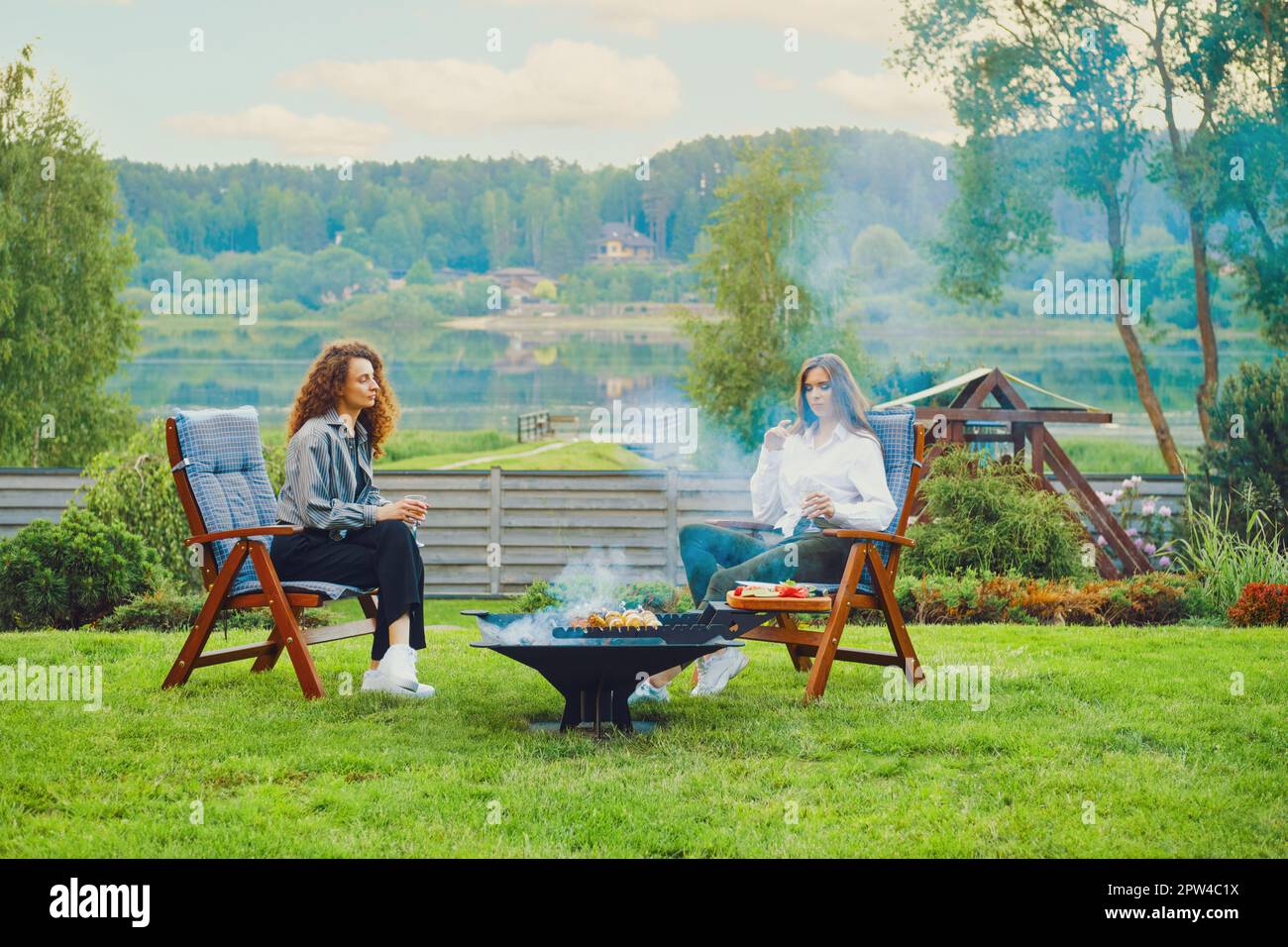 Two young women making meat and vegetables skewer in backyard Stock ...