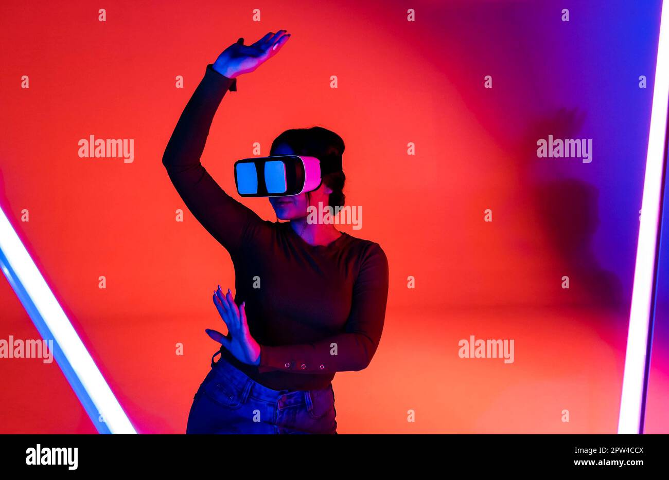 Happy female in VR headset smiling and exploring virtual reality under ...