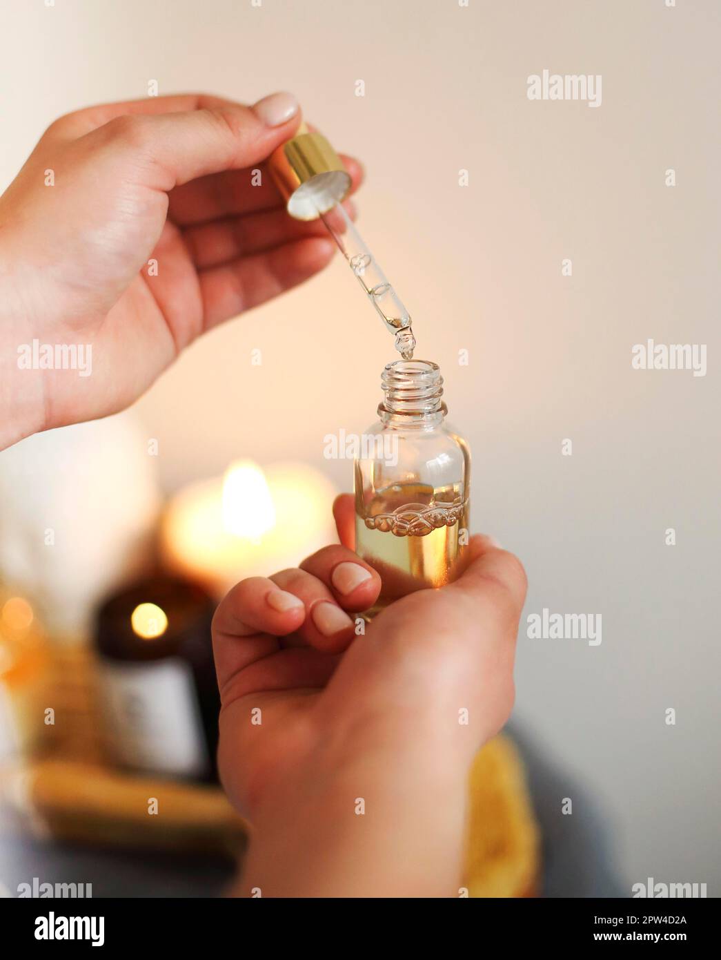 Crop masseuse using pipette with massage oil placed on tray with ...