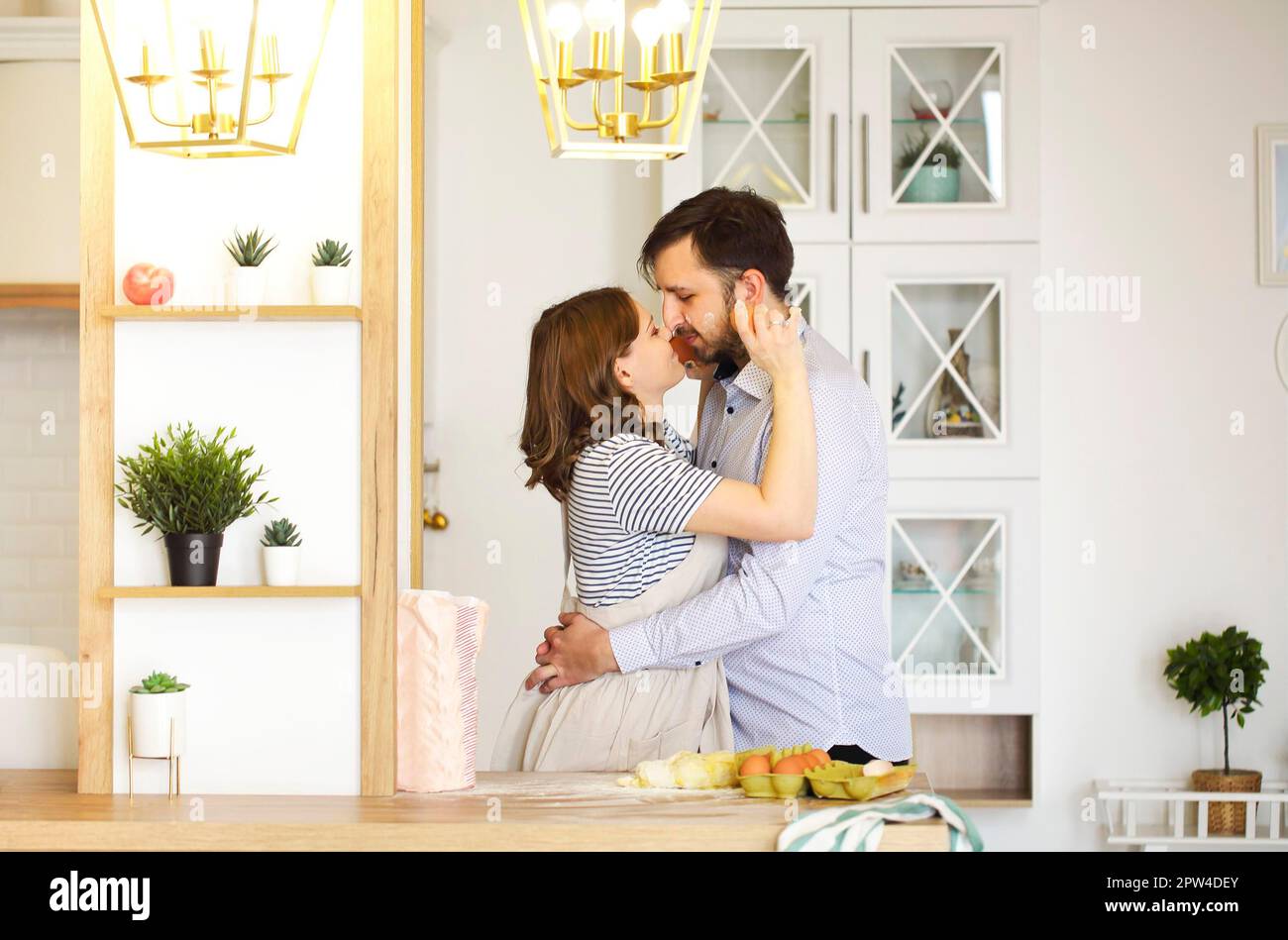 Side view of delighted couple in love hugging in kitchen while cooking ...