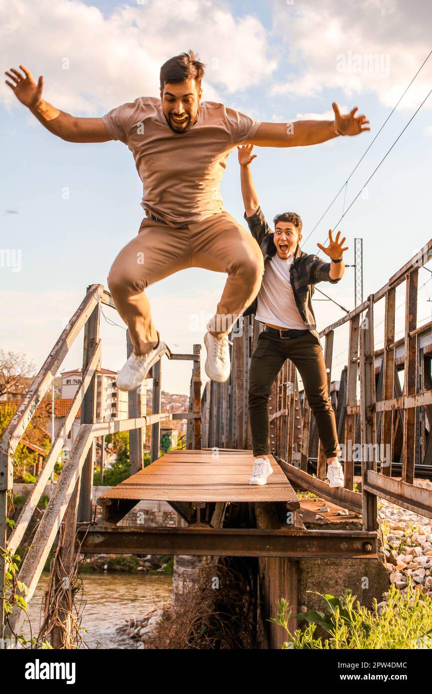 Caucasian teenager jumping from train tracks on a rusty train bridge ...