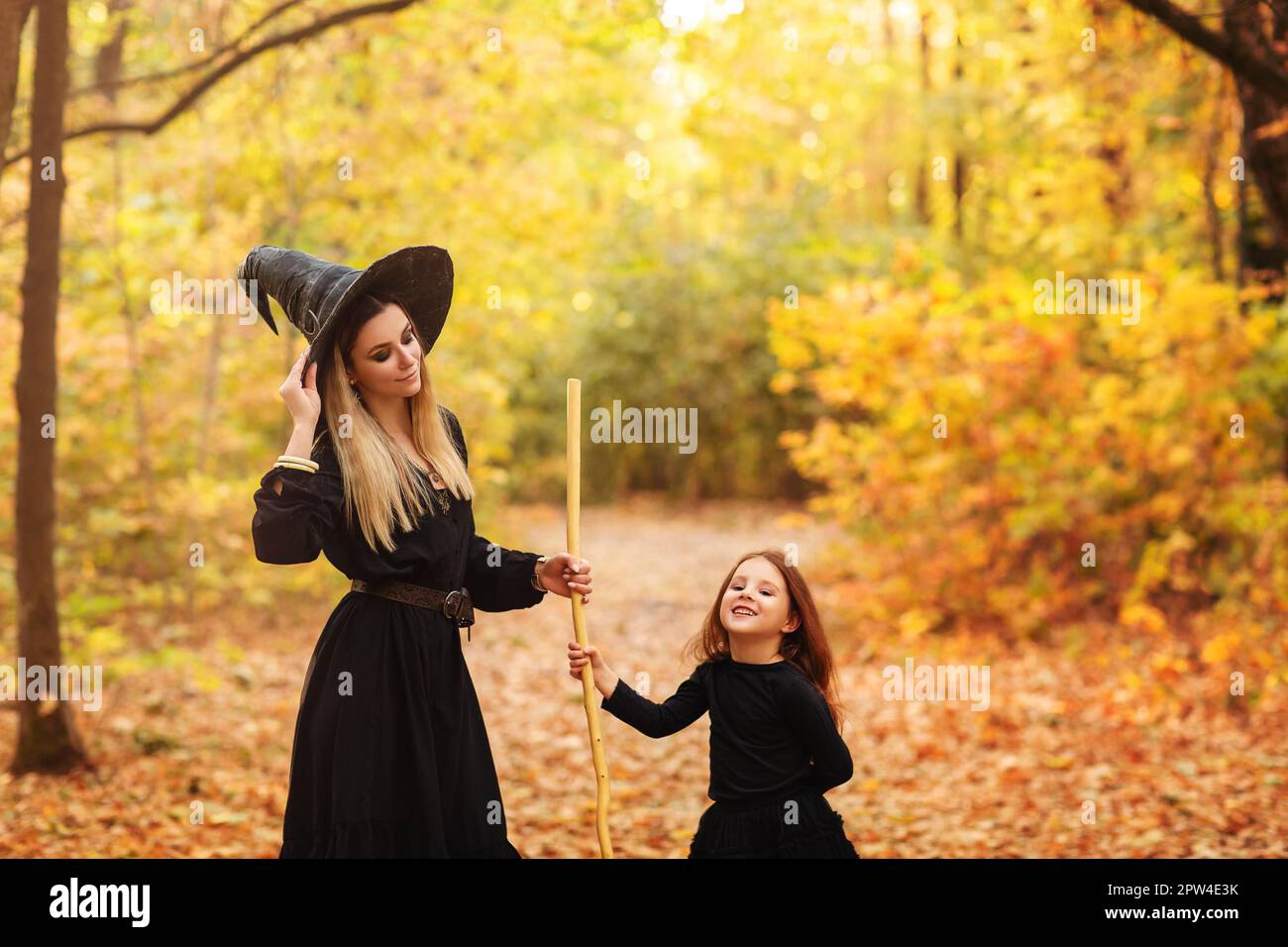 Full body woman and girl in witch costumes sweeping withered leaves ...