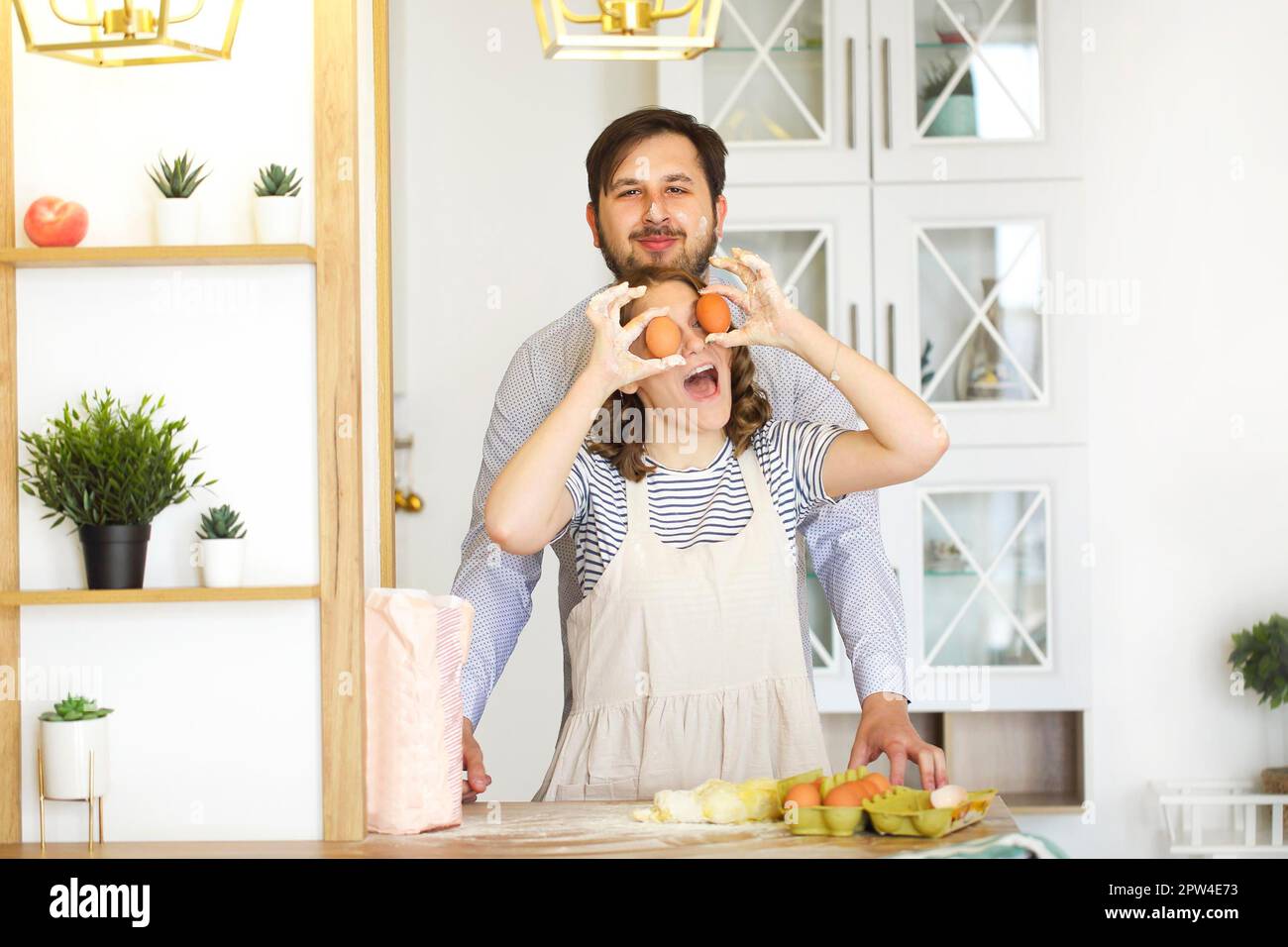 Side view of delighted couple in love hugging in kitchen while cooking ...