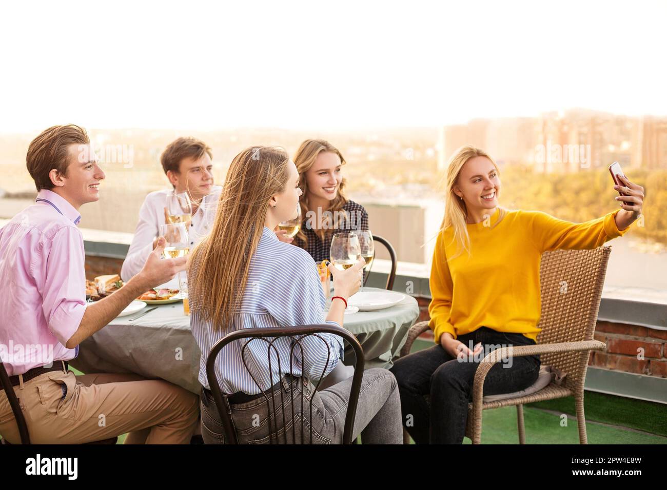 Group of five cheerful young people having dinner in restaurant ...