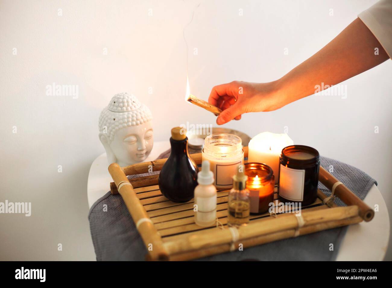 Female hand holding burning incense over wicker bamboo tray with ...