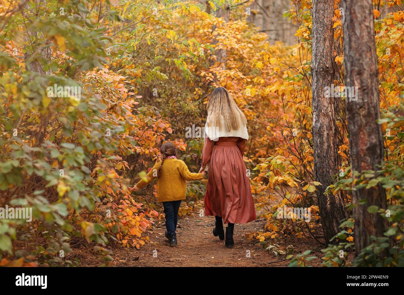 Rear view or young family, mother and little daughter, on walk in ...