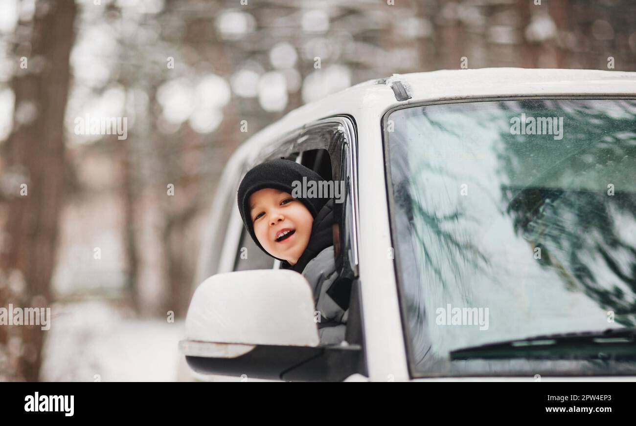 Excited little boy in black beanie and warm clothes sticking head out ...