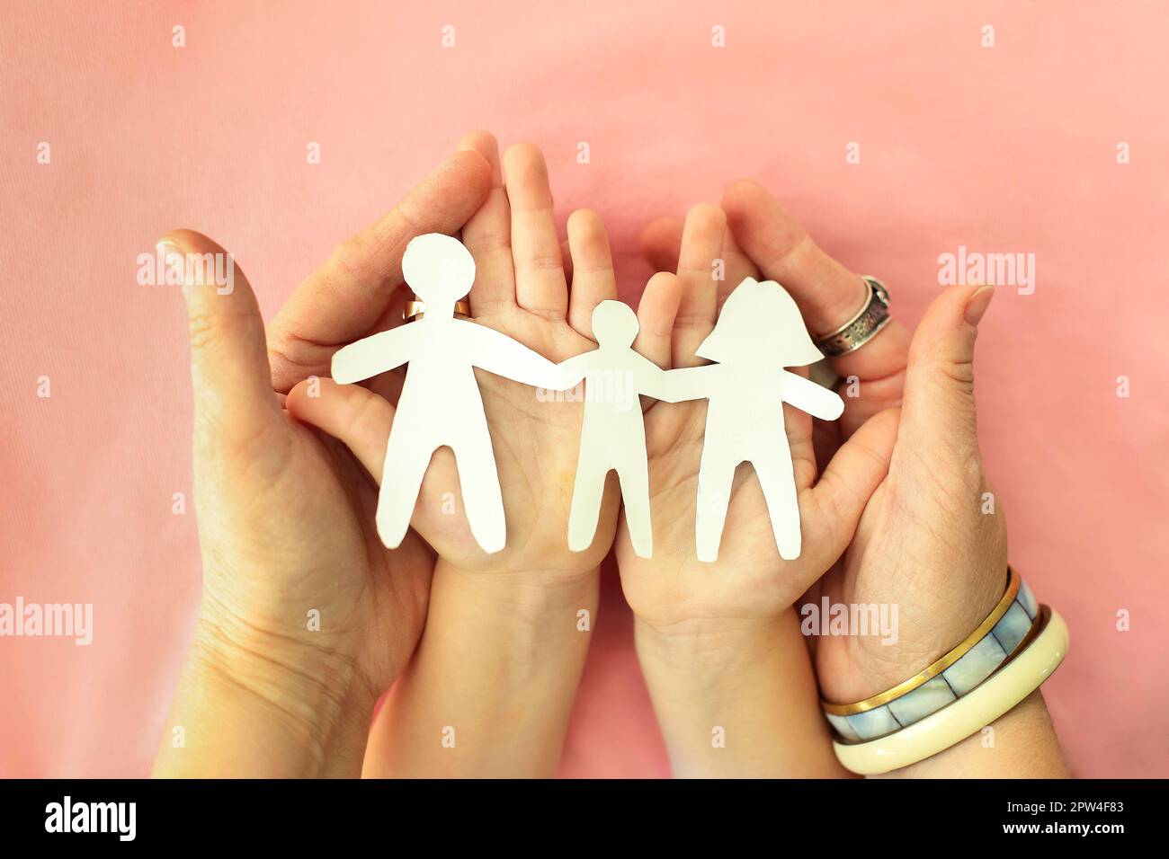 Cropped shot of mother, father and child holding family paper cut out ...