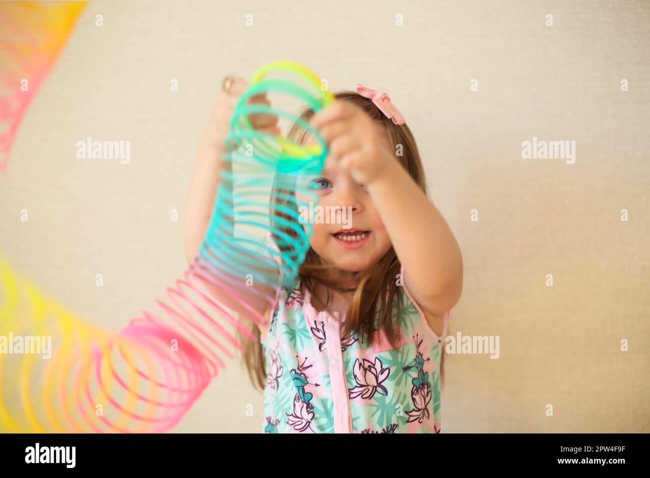 Cute adorable little girl playing with plastic rainbow magic spring ...