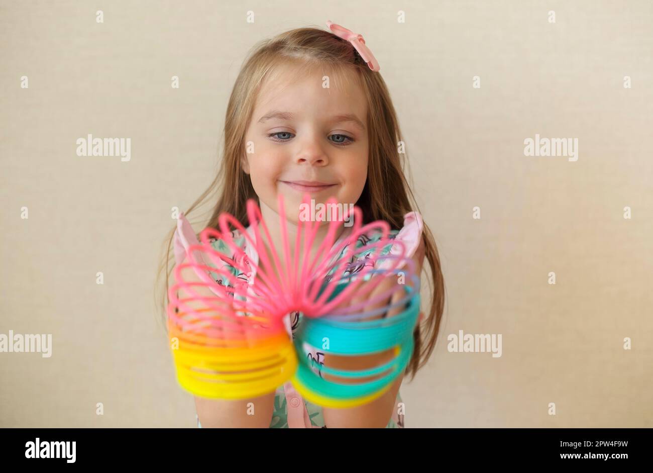 Cute adorable little girl playing with plastic rainbow magic spring ...