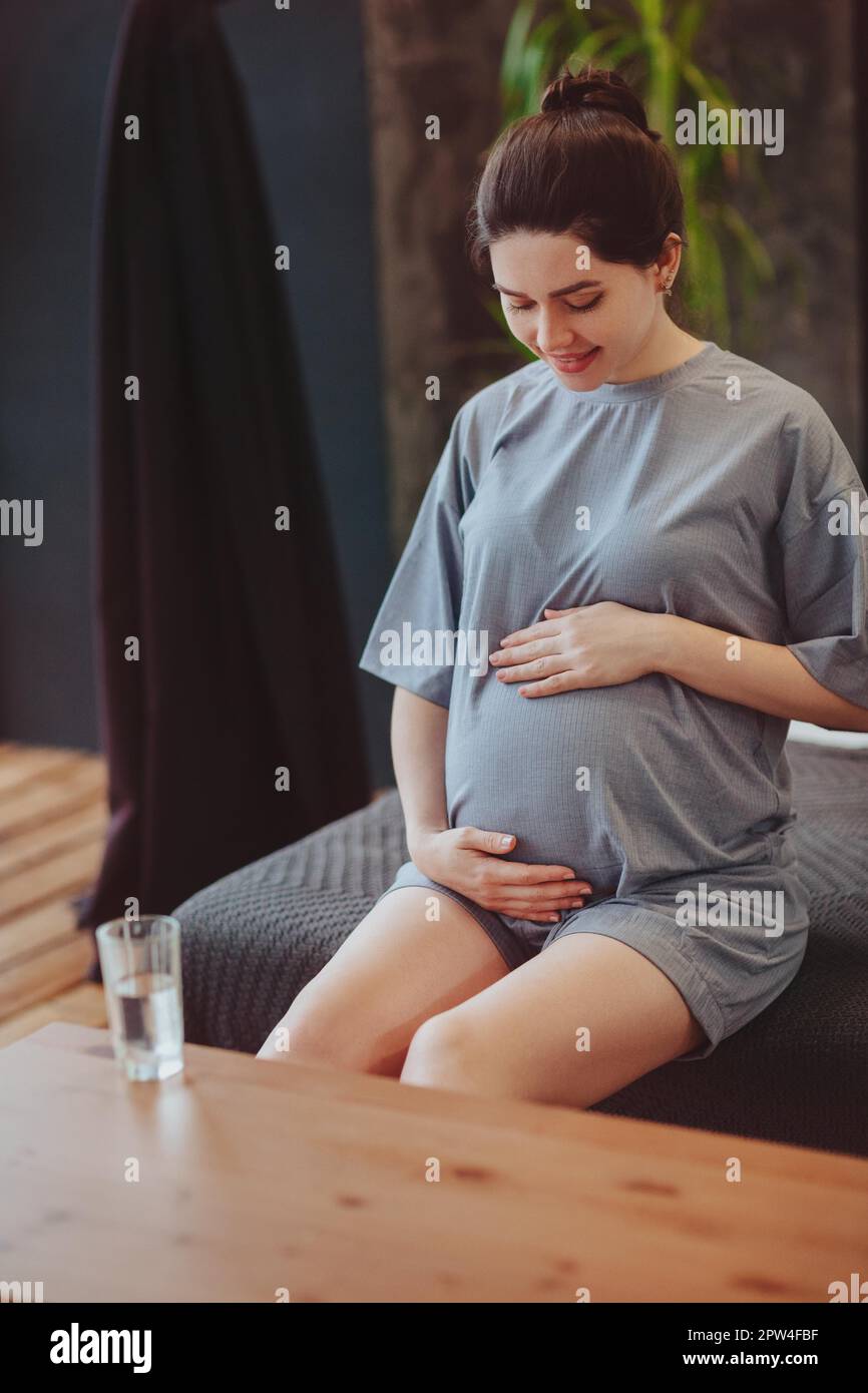 Healthy habits during pregnancy. Young happy pregnant woman in homewear ...