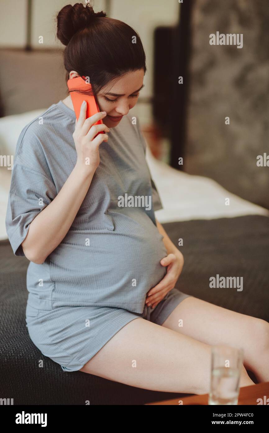 Young Smiling Pregnant Woman Touching Belly Talking On Mobile Phone
