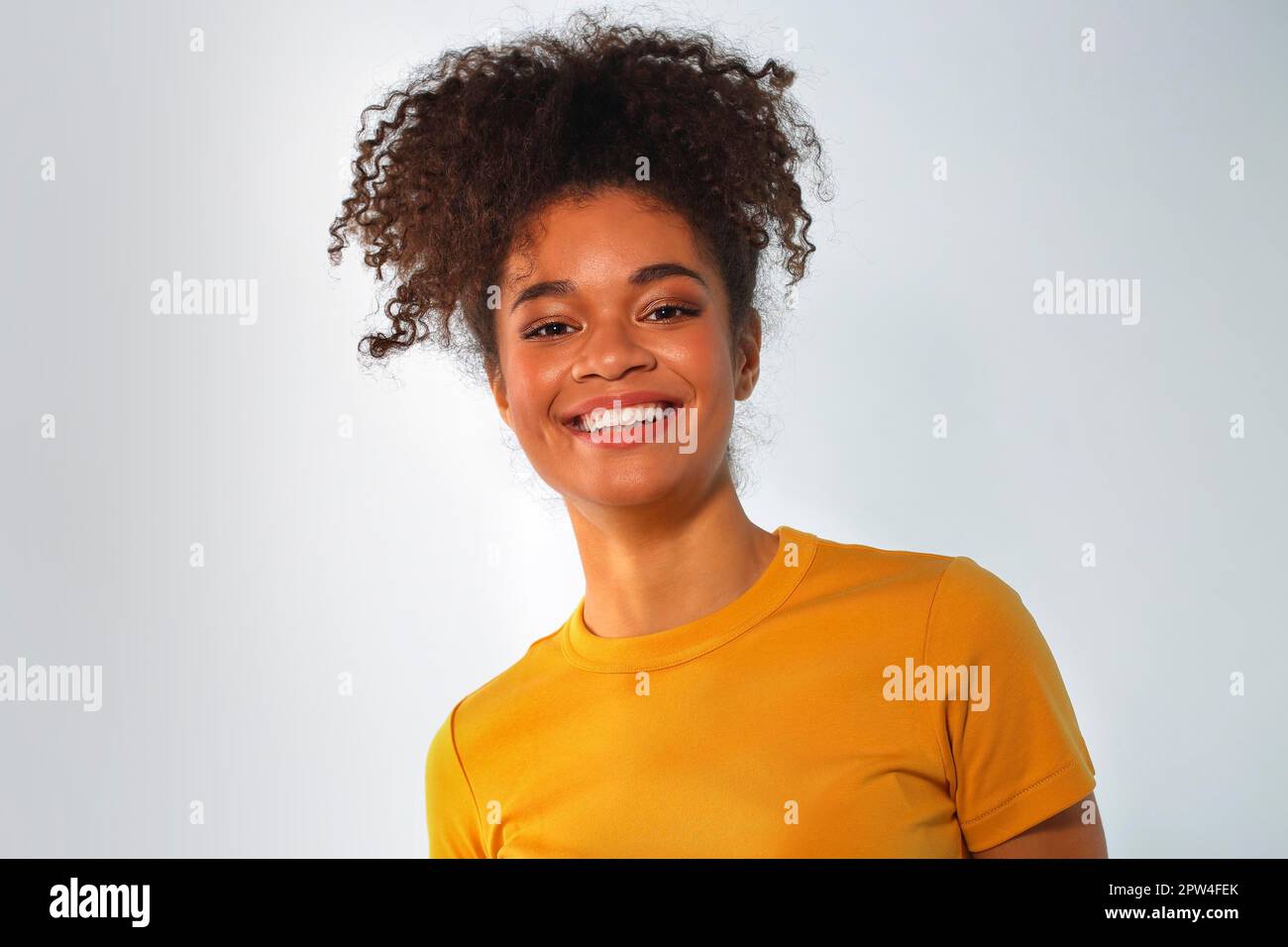 Overjoyed african american woman in bright yellow tshirt with curly ...