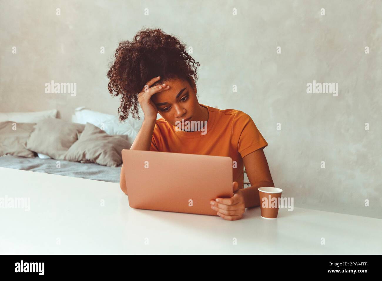 Tired flustrated African descent young girl sitting at desk in front of ...