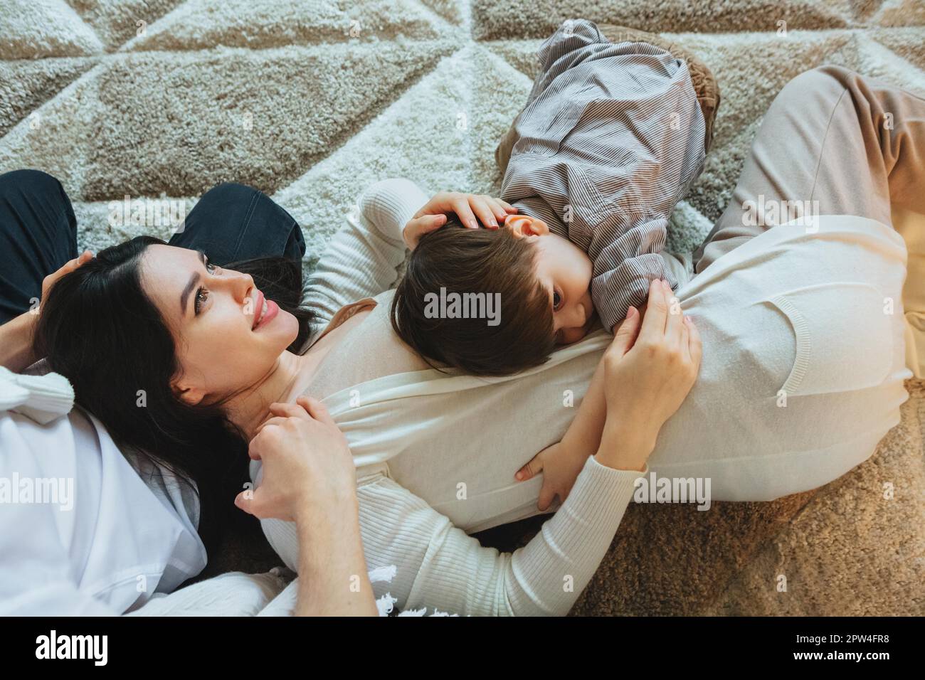 View from above of happy family with small kid expecting new baby ...