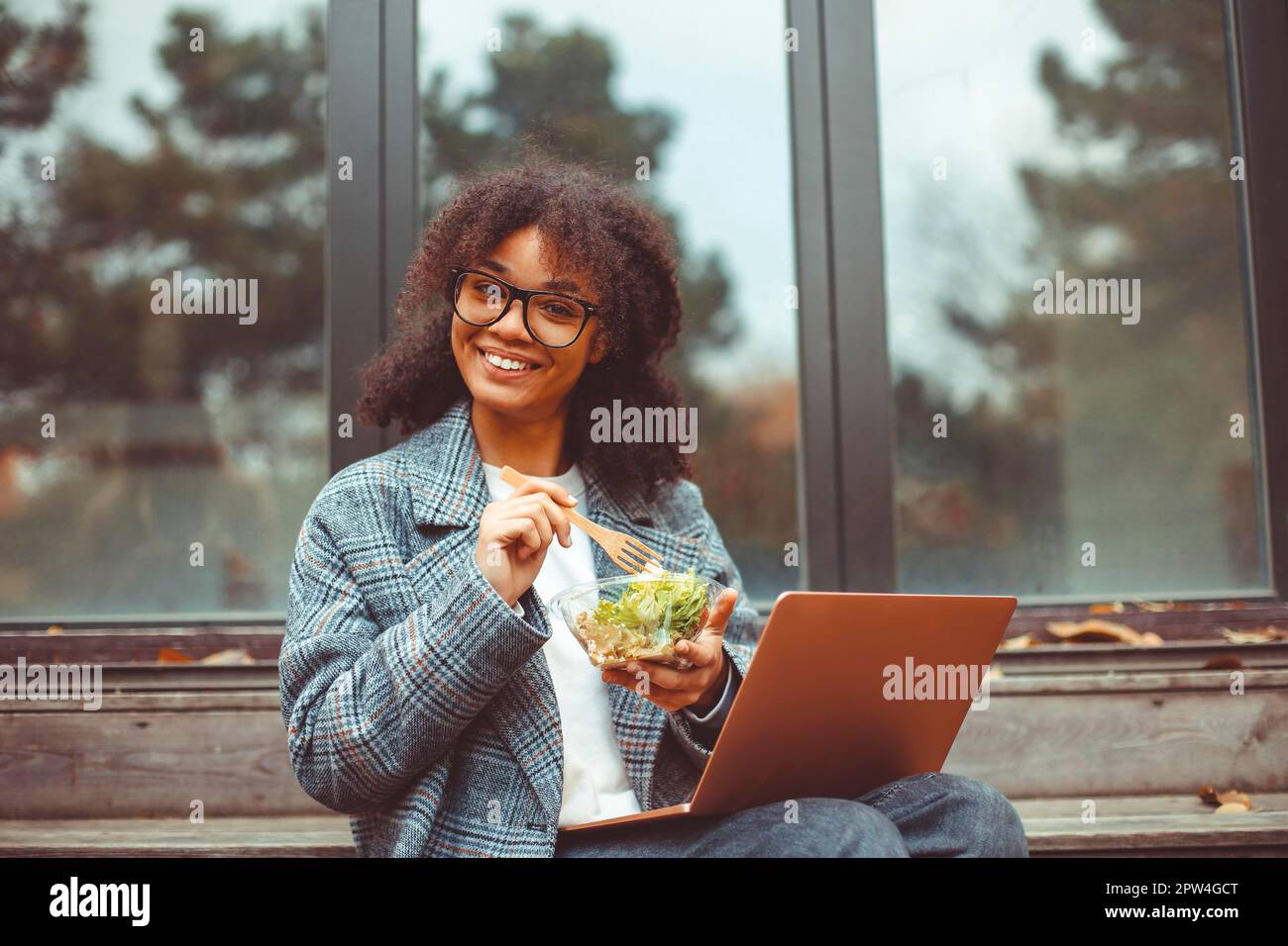 Happy african american woman eating salad, having healthy lunch while ...