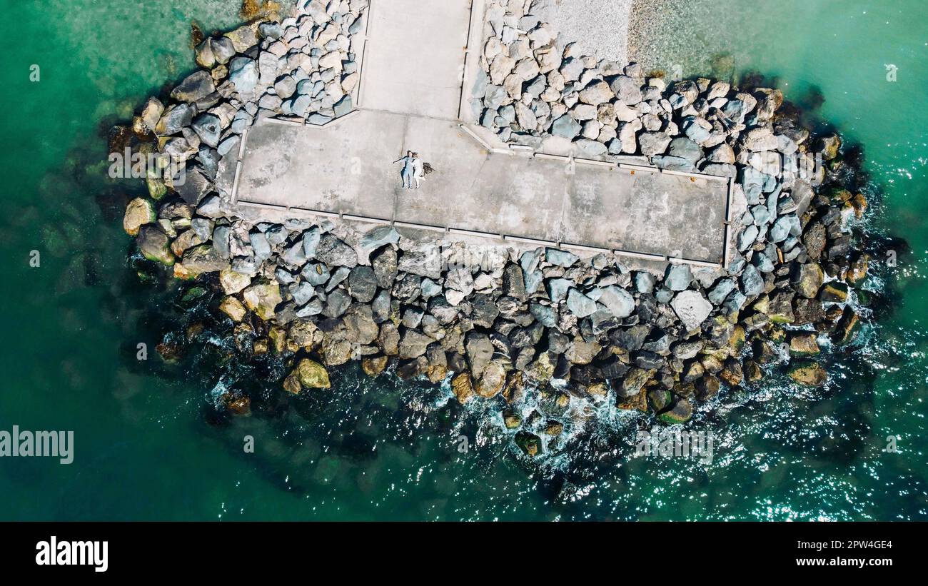 Happy romantic couple lying on the pier on sea with turquoise blue ...