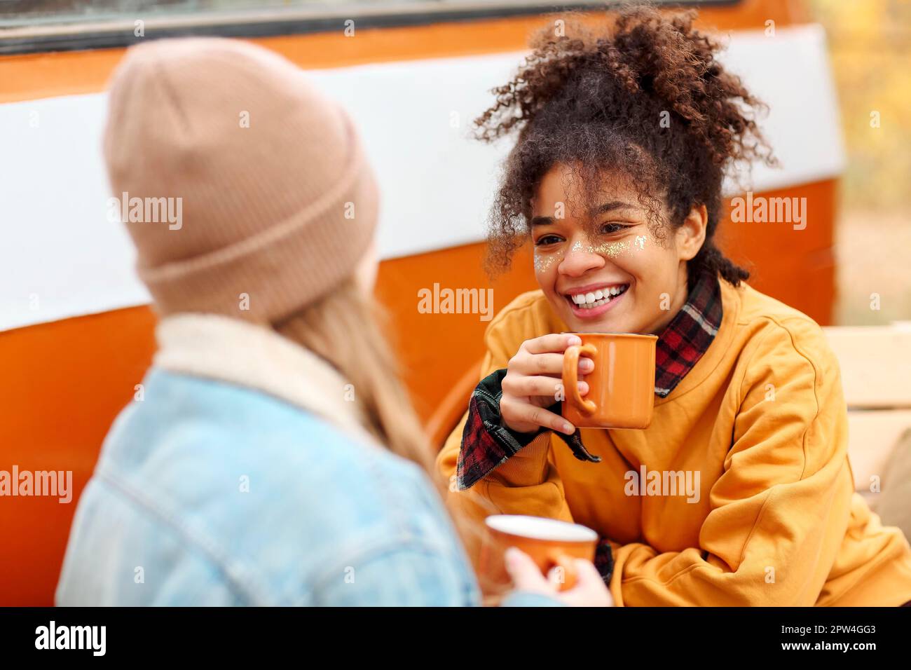 Two multiracial girlfriends talking sitting hi-res stock photography ...